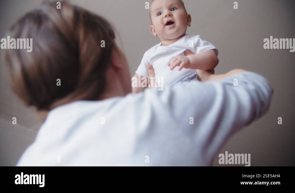 Mom lifts up a newborn baby. Loving mother plays with the child ...