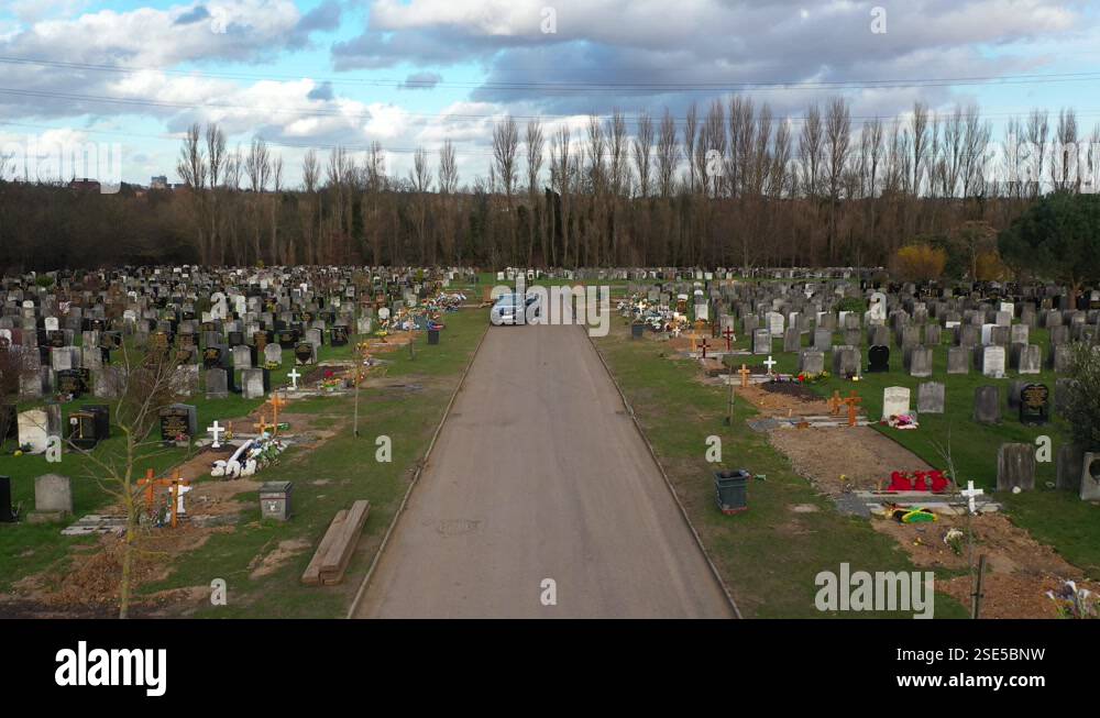 FLYING OVER A CAR REVEALING A FAMILY LEAVING CEMETRY AFTER VISIT ...