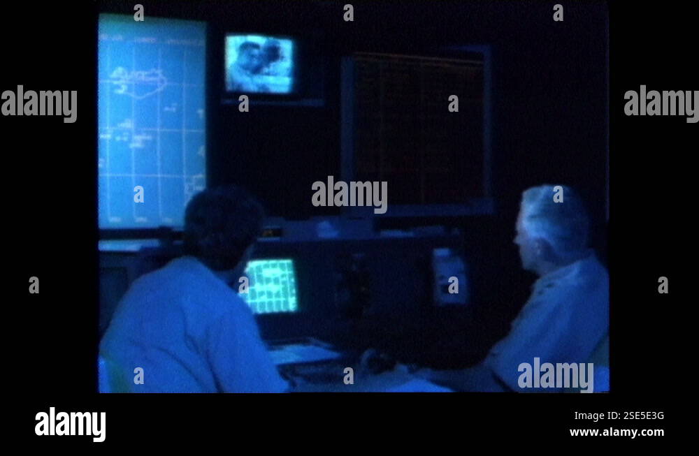 1980s: Two people in Navy control room watch person on monitor. Person ...