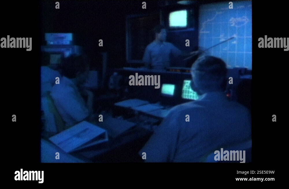1980s: Officer in Navy control room points to map on wall. Man writes ...
