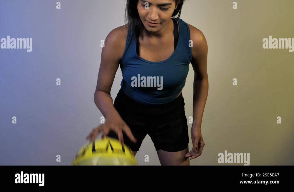 Indian woman football player bouncing the ball indoors - fit and active ...