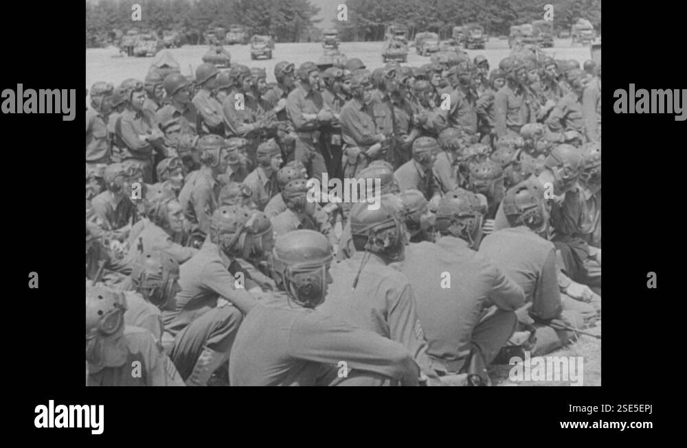 1940s: Group of soldiers sits on ground, listens to officers. Rows of ...