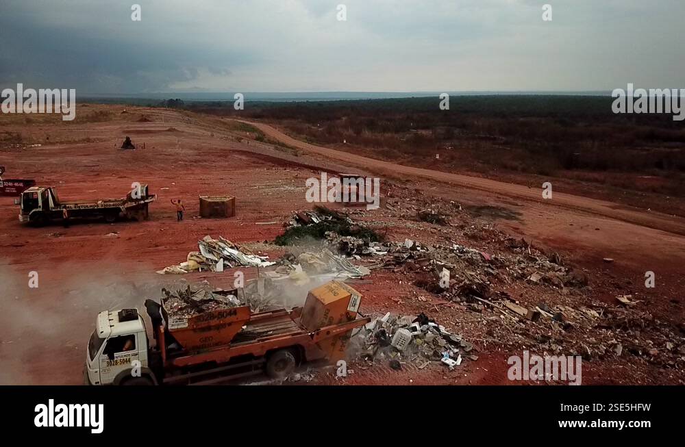 Dust rises up of the red dirt at a landfill as a dump truck unloads a ...