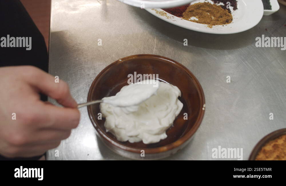 Chef prepares mediterranean starter yogurt dish. Adding yogurt from ...