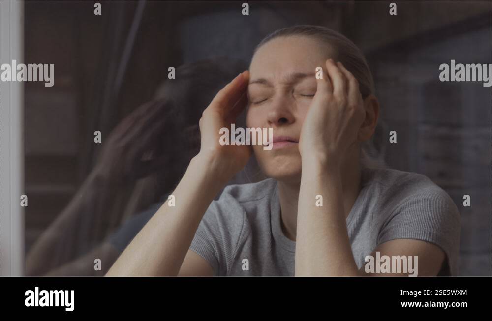 Women sitting by the window who are bothered by migraines. The woman ...