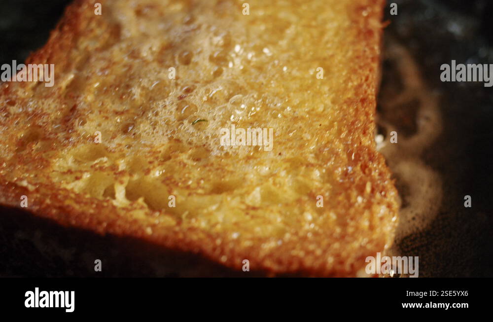 Golden bread toast fried in a hot pan with butter bubbles in slow ...