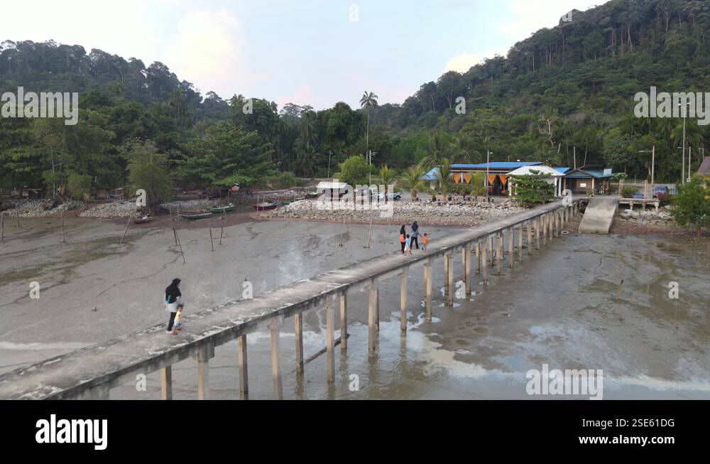 Drone flying backward from jetty. Woman is walking on jetty in Teluk ...