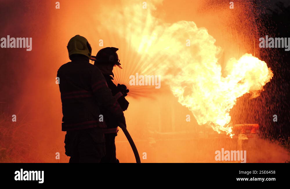 Firefighter in full gear operating a fire hose at Fire station Stock ...