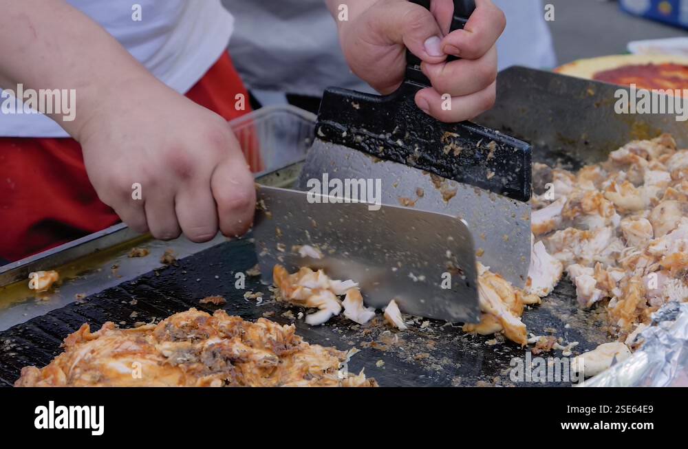 Chef cutting chicken meat on grill at food festival: slow motion, close ...