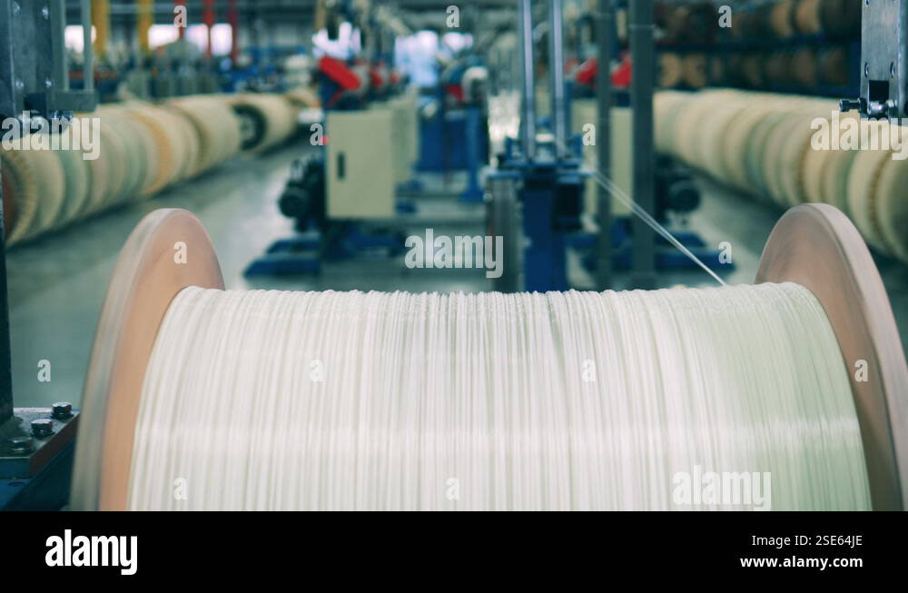 White-colored electric wire unwinding from a spool at factory Stock ...