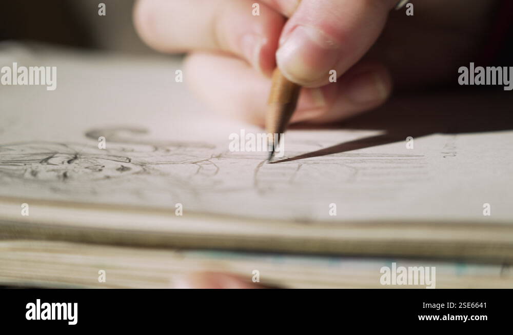 Person sketching with pencil, hand-drawing cartoon character on paper ...