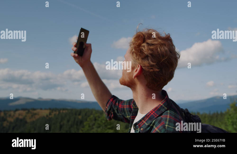 Hiker holding smartphone in hand on top of mountain. Guy catching ...