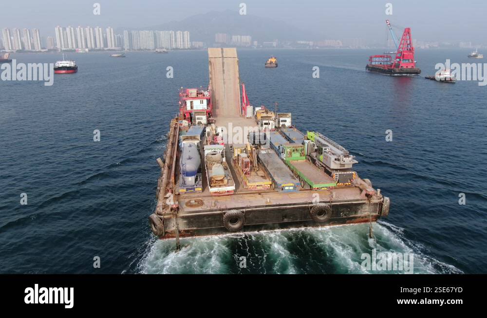 Barge loaded with Concrete mixer trucks pulled to port by a Tugboat in Stock Video Footage - Alamy