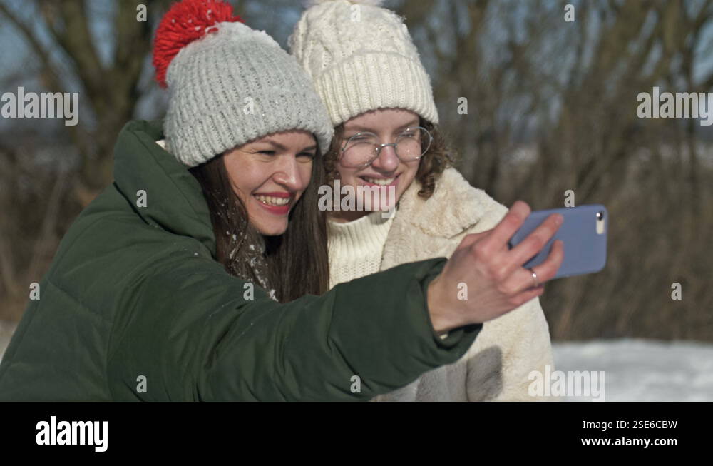Young woman and her teenage daughter take a selfie during a winter walk ...
