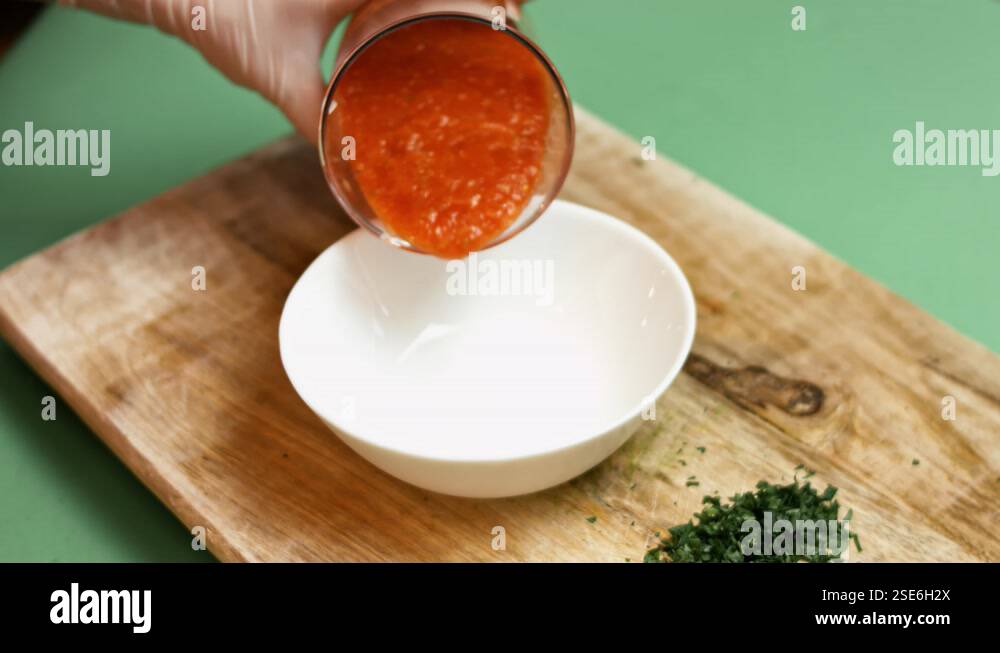 Pouring mixed ingredients for salsa from glass into a bowl. Process of ...