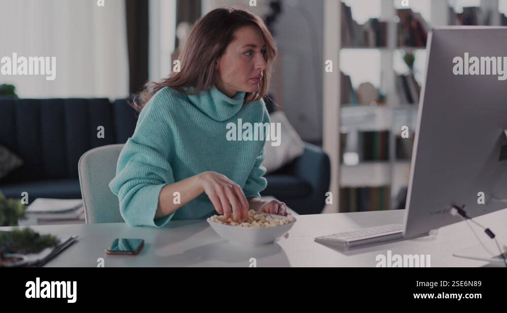 Curious young excited woman sitting at home, ing computer watching ...