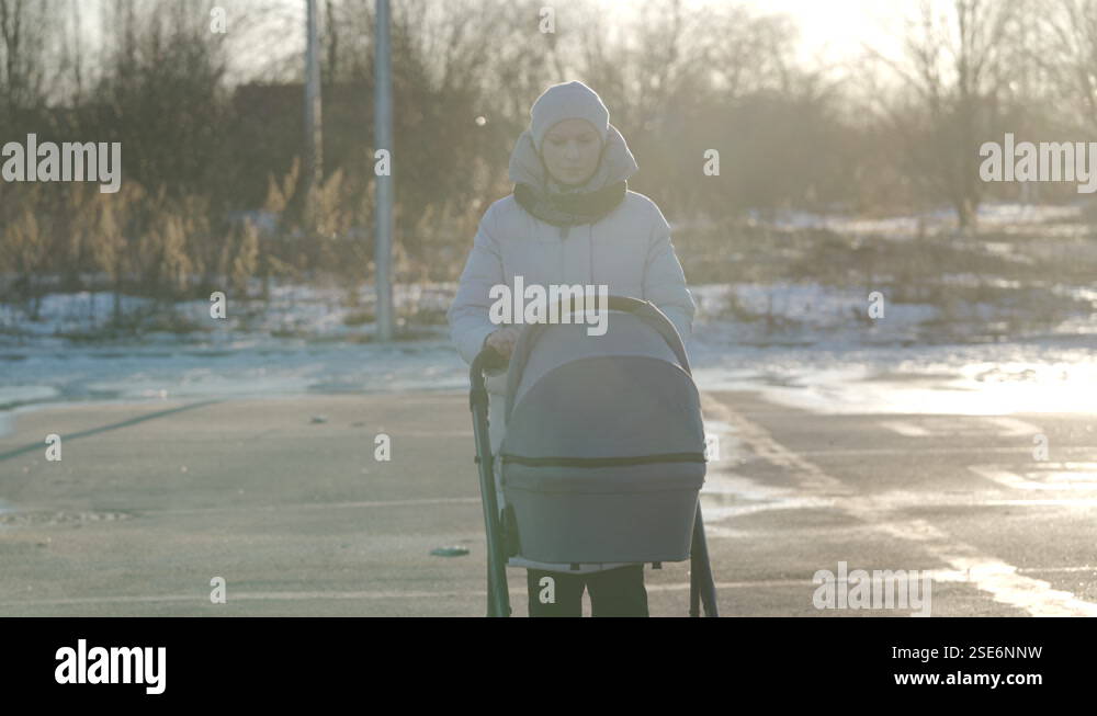 Mother with a baby carriage walking down the street woman pushing baby ...
