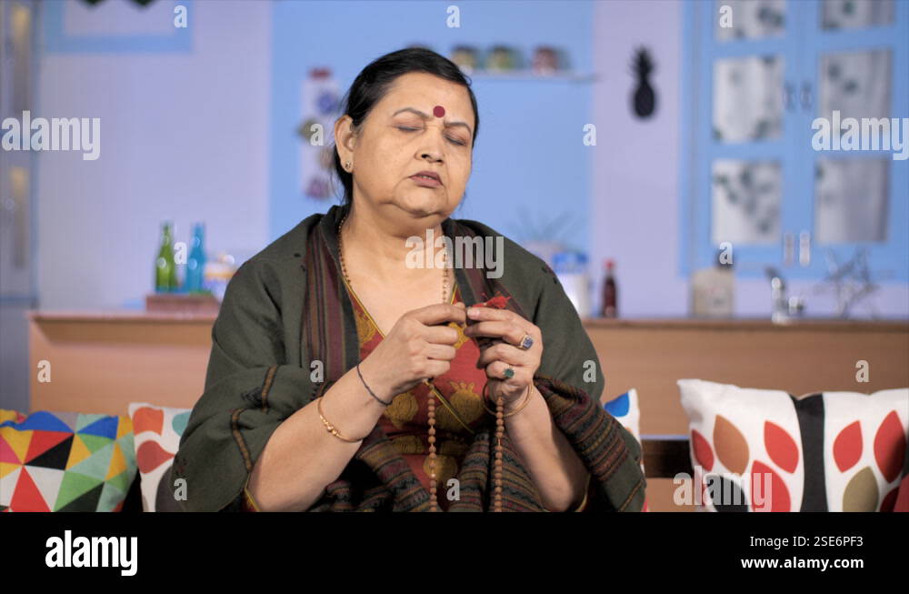 An aged Hindu woman chanting hymns / Mantras - religious faith concept ...