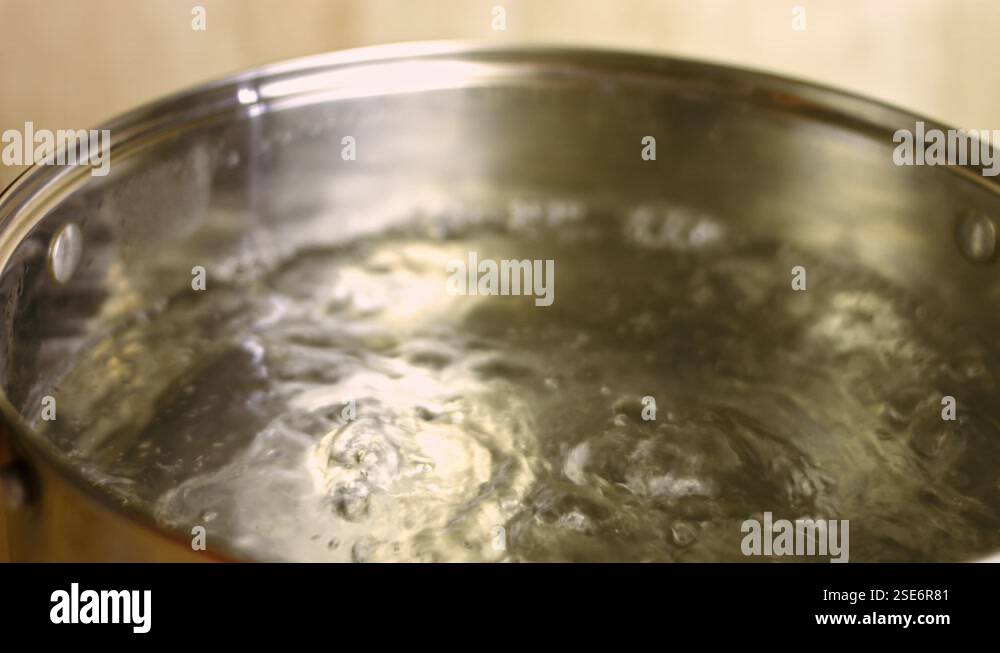 Pouring a tablespoon of salt into boiling water in a pot. Process of ...