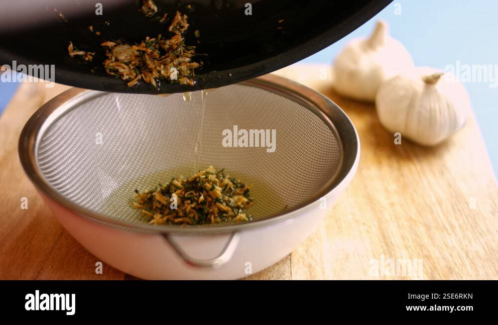Straining through a sieve the fried garlic and chopped rosemary leaves ...