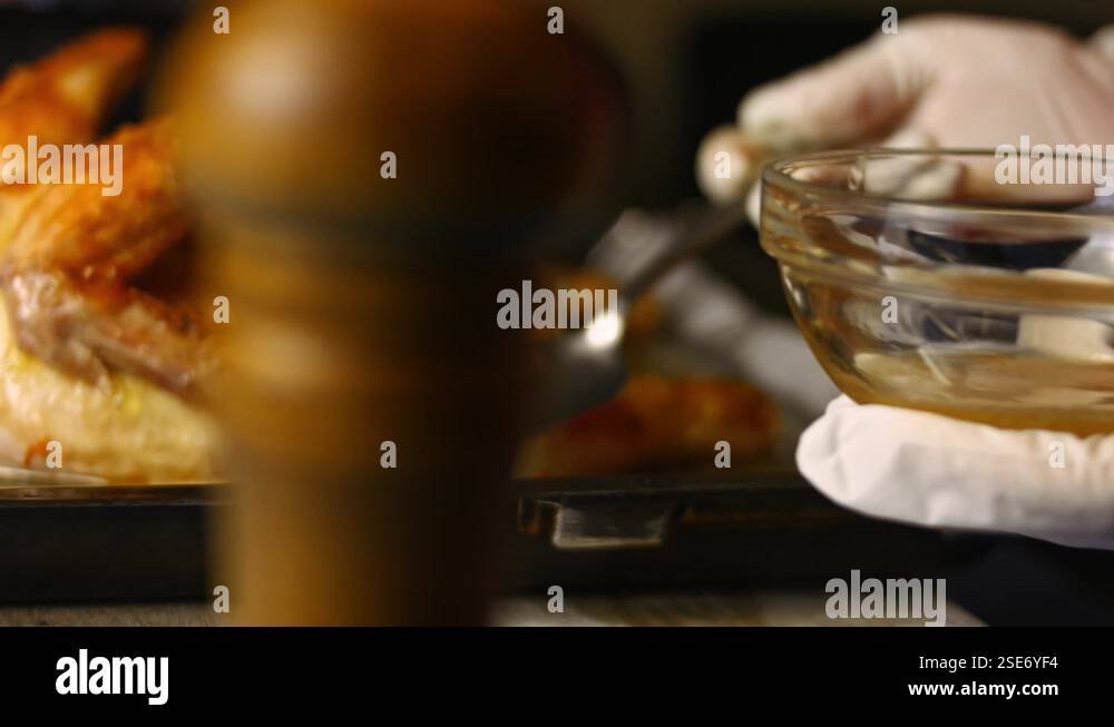 Female chef gathering melted fat from a big spatchcocked oven roasted ...