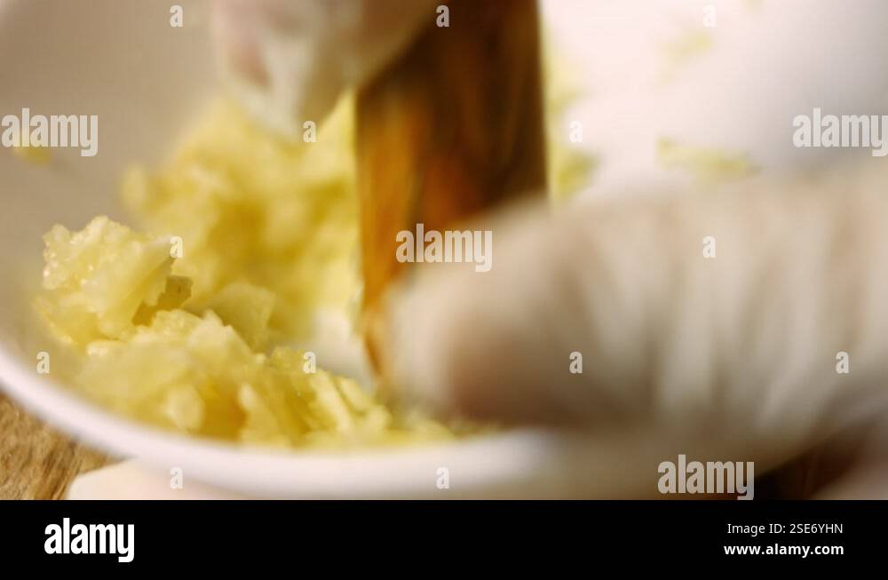 Female hands in gloves pressing peeled cloves in a bowl. Process of ...