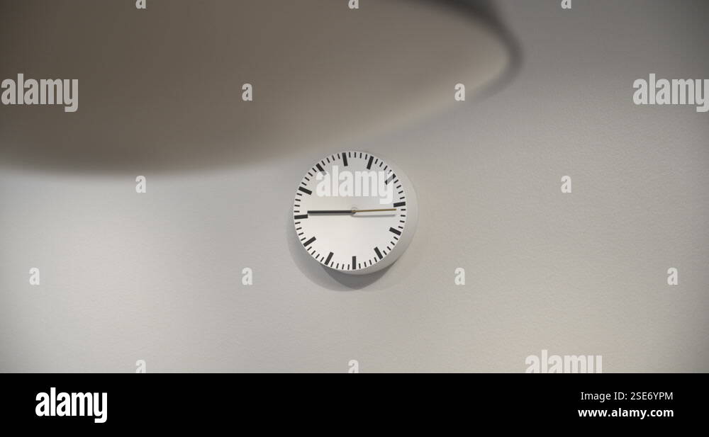 Dolly shot of a classic black and white clock hanging on a white wall ...