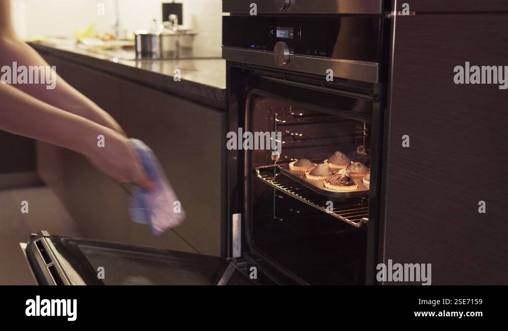 Woman's hand opens oven and takes out burnt cookies, smoke from ...