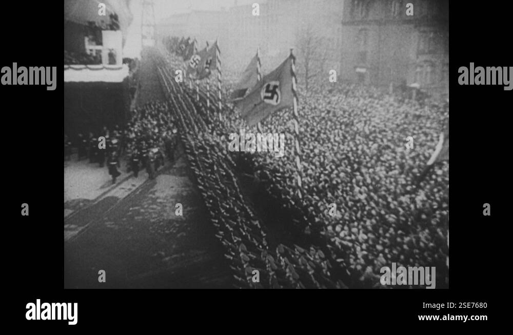1930s Germany: Title card. Nazi parade. Men give Nazi salute. Flag with ...