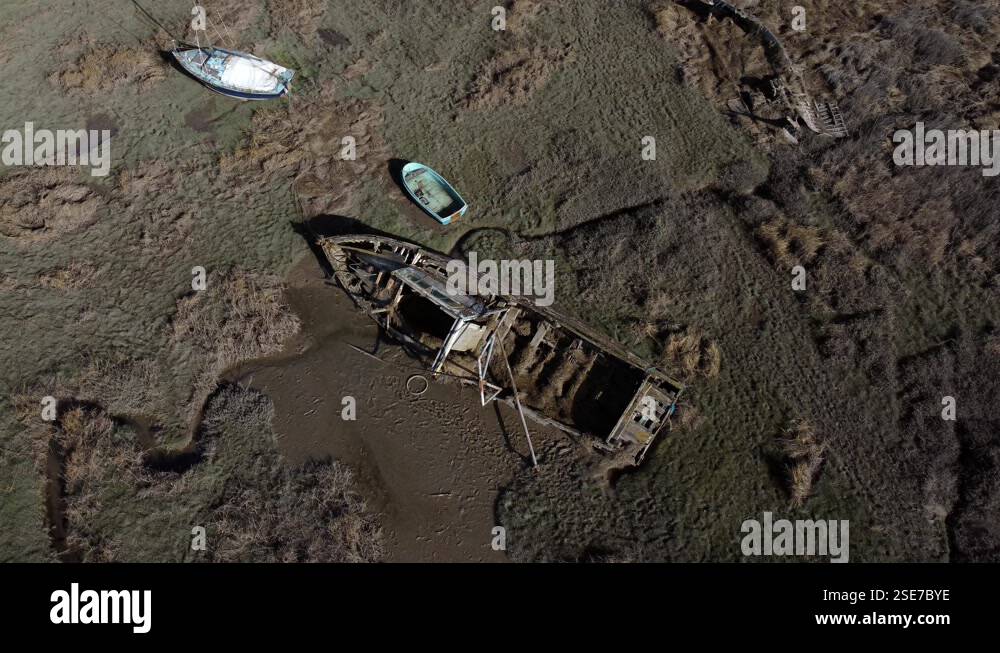 Abandoned weathered wooden fishing boat wreck shipyard in marsh mud low ...