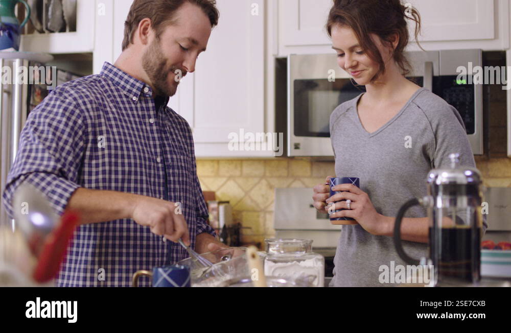 A young couple in a kitchen cooking breakfast together, flirting Stock ...