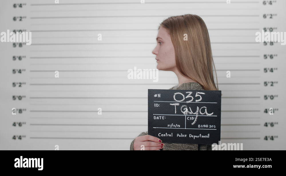 Side profile mugshot of female person holding sign while being ...