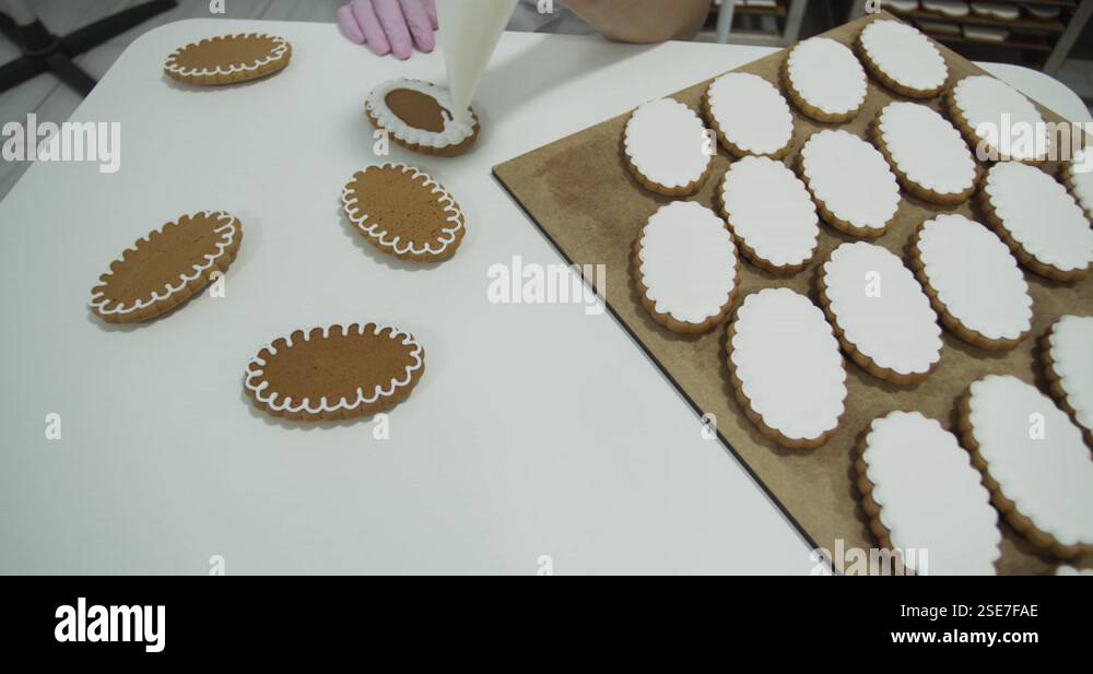 Lots of fresh gingerbread cookies and a confectioner is putting icing ...