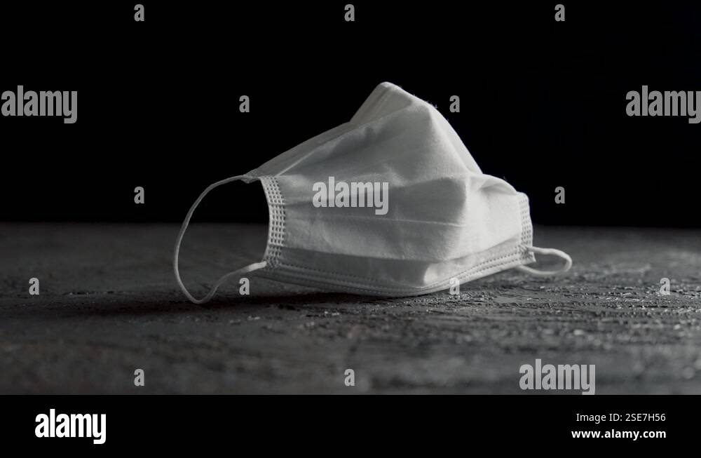 Face mask in white on a table with black background filmed on a slider ...