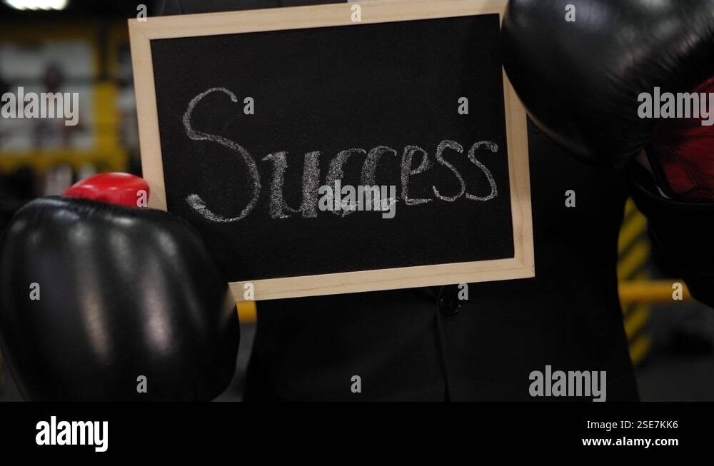A businessman in a boxing gloves holds a board with the inscription ...