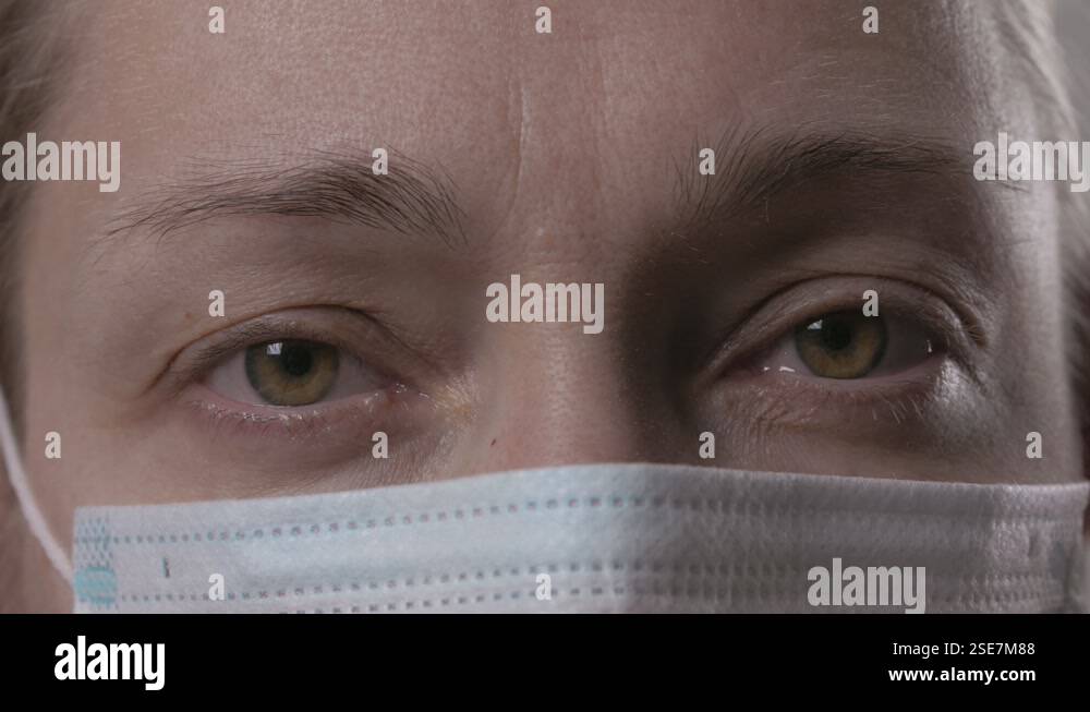 Looking at the camera, the woman puts on a mask, close-up. The face in ...
