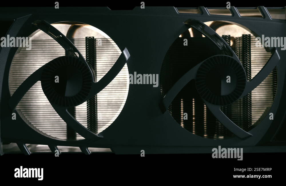 Two cooling fans of a computer video card rotate in a backlight beam ...
