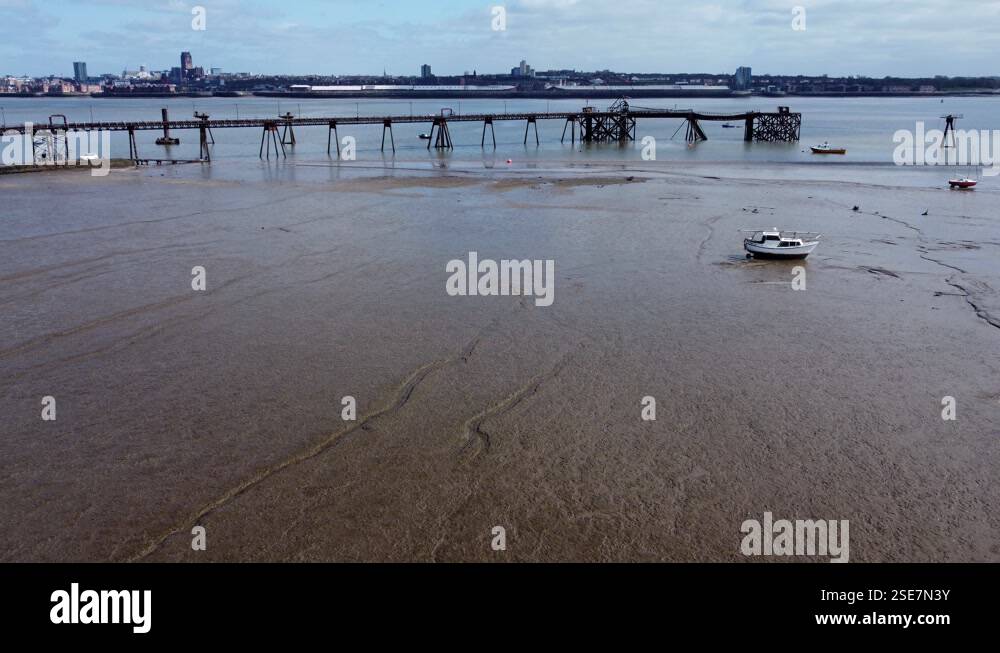 Small fishing boat aerial reverse left view of stranded vessel on muddy ...