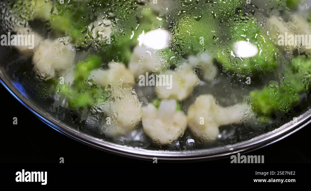 The fresh cut vegetables are fried on a frying pan through a glass ...