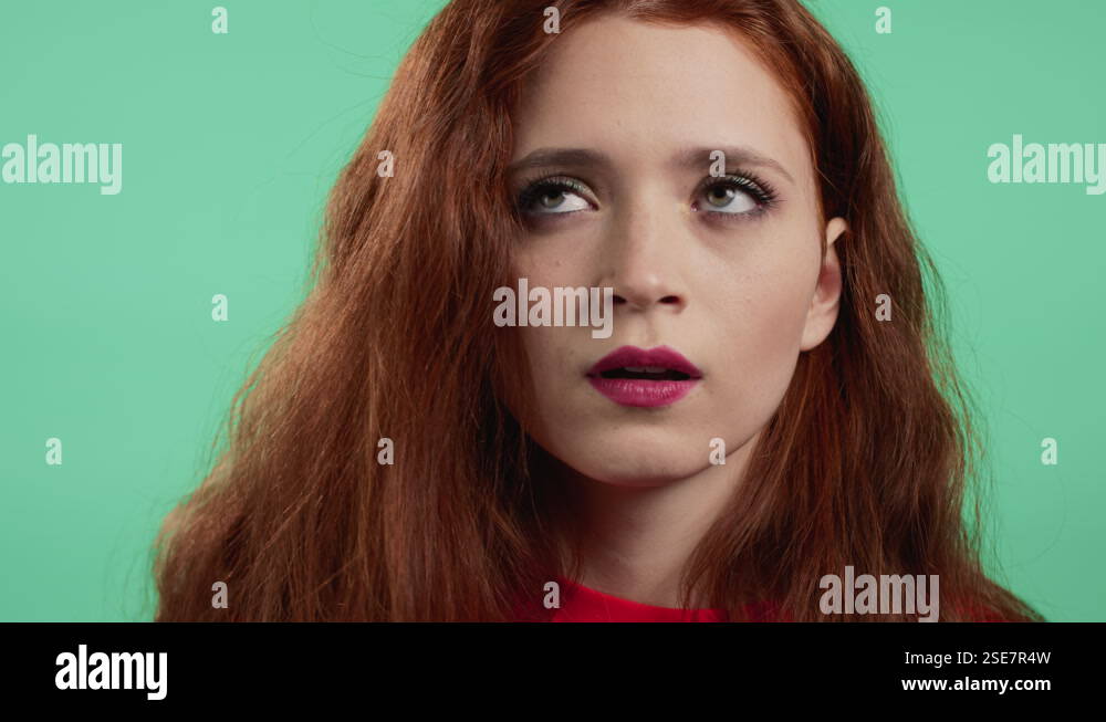 Young woman sneezes into tissue. Isolated girl on green studio ...