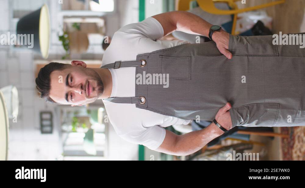 Vertical footage of handsome young Caucasian guy employee in apron ...
