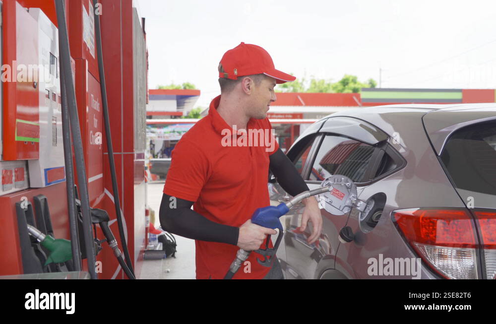 A Caucasian man, people, worker filling up fuel by using petrol pump at ...