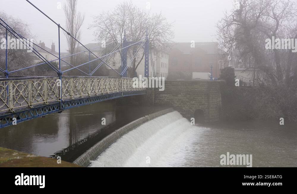 Ornate Victorian iron pedestrian bridge over a weir on the river Leam ...