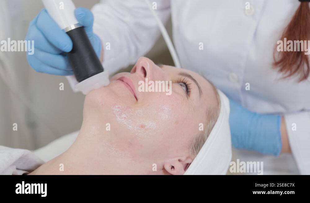 A professional beautician treats a woman's face with a carboxytherapy ...