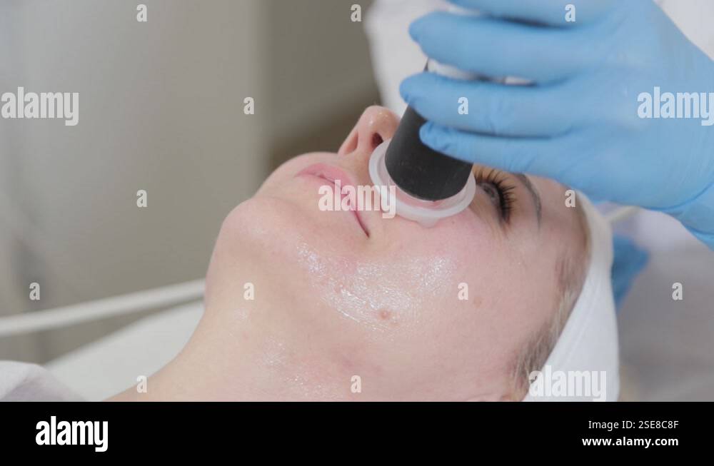 A professional beautician treats a woman's face with a carboxytherapy ...