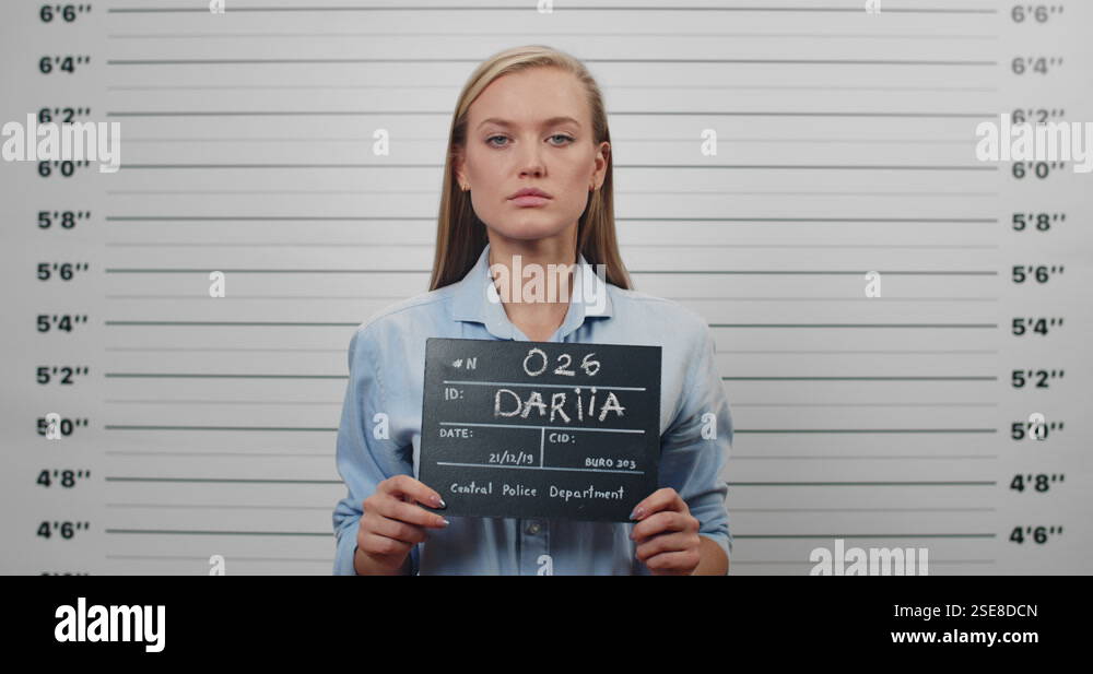 Mugshot of beautiful arrested woman holding sign for photo in police ...