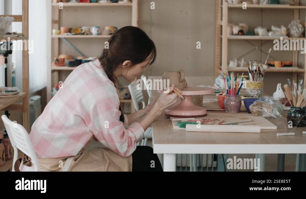 Woman potter forms a clay teapot in ceramic workshop. Pottery for tea ...