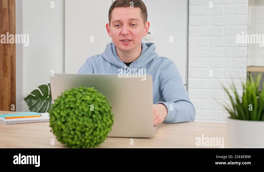 Man communicates via zoom video conference via laptop, gestures with ...