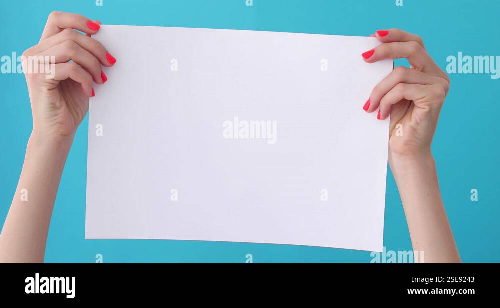 finger points on blank sheet of paper in female hand isolated on blue ...
