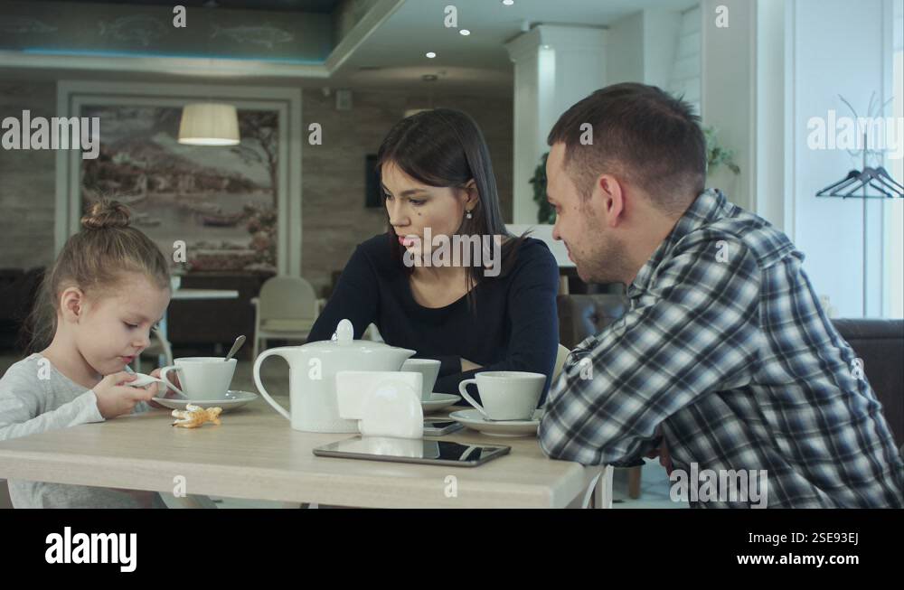 Family Enjoying tea In Cafe Together Father and mother talking looking ...